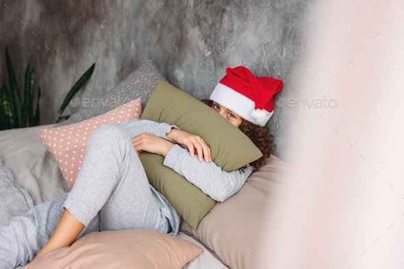 Curly haired beautiful tween girl in Santa hat and pajamas sitting on ...