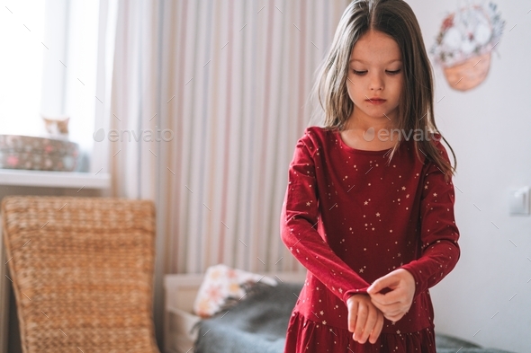 Pretty tween girl with long hair in red dress in children's room at ...