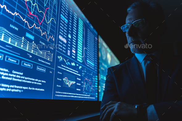 The old businessman standing near the big blue screen with graphics ...