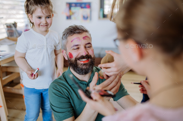 Three little girls putting on make up on their father, fathers day with ...
