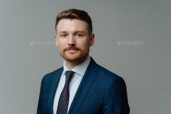 Handsome unshaven man in suit posing against grey background Stock ...