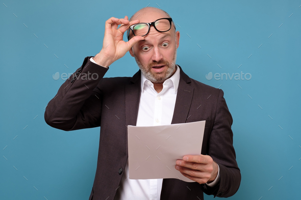 Shocked italian man in suit analyzing reports posing on blue studio ...