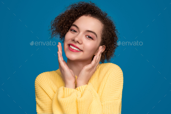 Positive young lady smiling and touching cheek in blue studio Stock ...