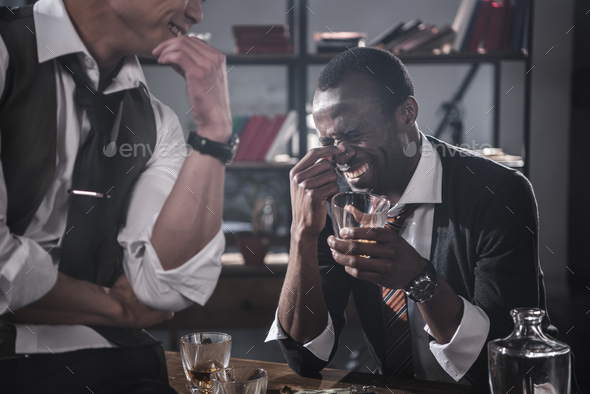 cheerful colleagues drinking alcohol while spending time together after ...