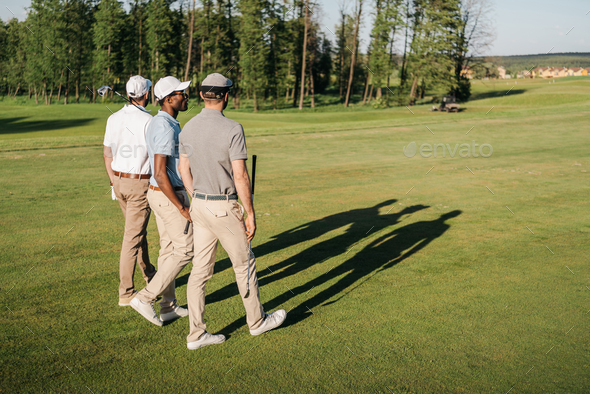 Back view of three golfers in caps walking on green lawn Stock Photo by ...