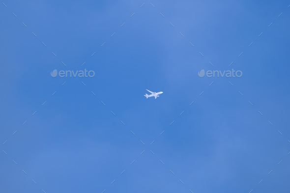 Distant passenger jet plane flying on high altitude on clear blue sky ...