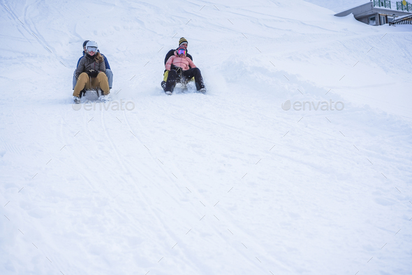 Crazy happy friends having fun with sledding on snow high mountains ...