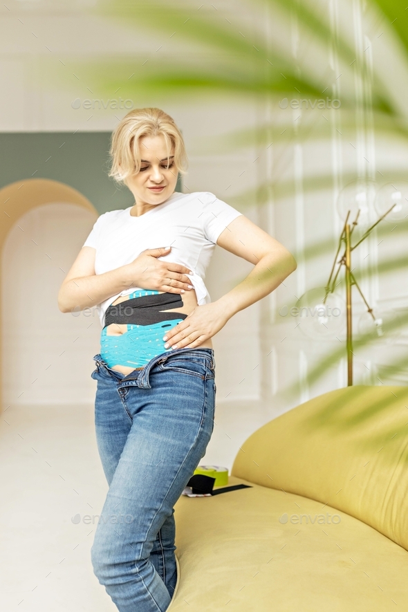 A woman glues a medical tape for burning, slimming in the abdomen ...