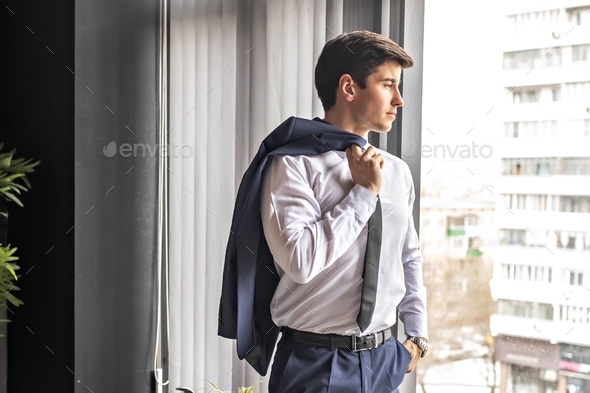 An employee in a formal suit in the office by the window. Businessman ...