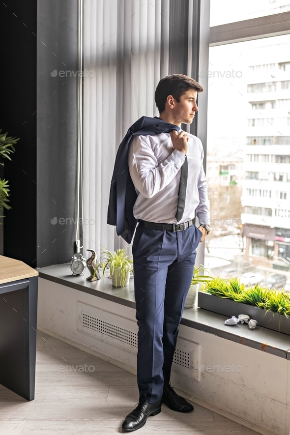 An employee in a formal suit in the office by the window. Businessman ...