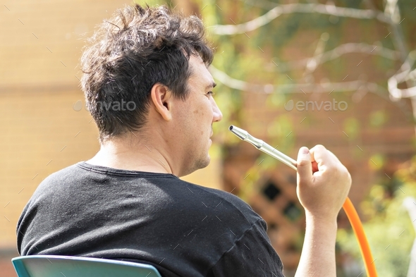 Portrait of a young man in the backyard of his country house smoking a hookah Stock Photo by ...