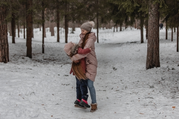 Family winter walk in the forest. Mother and daughter are having fun in ...