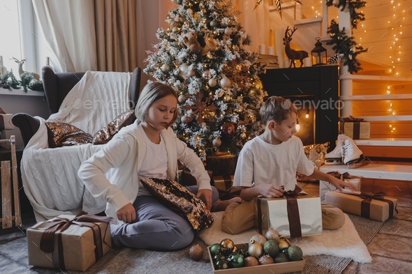 Happy family decorating a Christmas tree with boubles and presents in ...