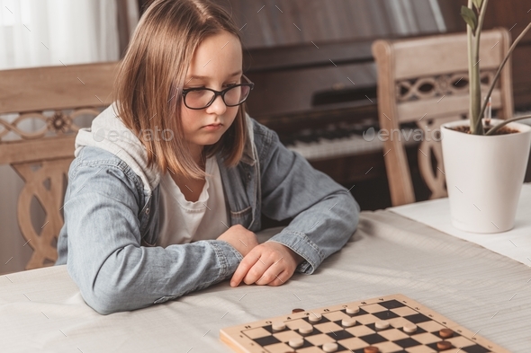 Cute girl playing checkers board game with her father at home. Stock ...