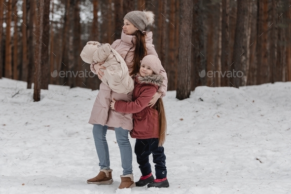 Family winter walk in the forest. Mother and daughter are having fun in ...