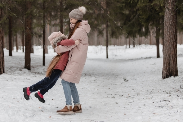 Family winter walk in the forest. Mother and daughter are having fun in ...