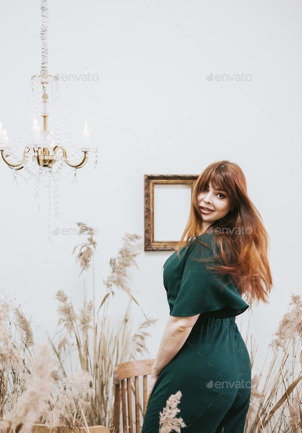 young woman plus size model sits on a chair wearing a green suit in a ...