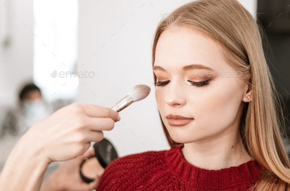 process of face makeup brush alignment of the face tone on a beautiful ...