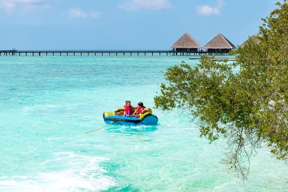 children a boy and a girl in life jackets ride on a water tube and have ...