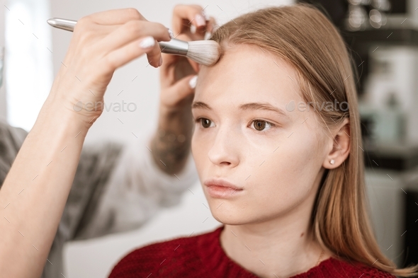 process of face makeup brush alignment of the face tone on a beautiful ...