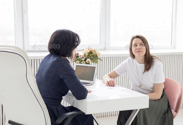 two young women conduct a coaching session in home office in light ...
