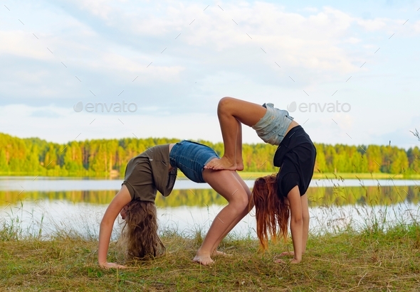 two girls do gymnastic exercises outdoor in a picturesque place by the ...