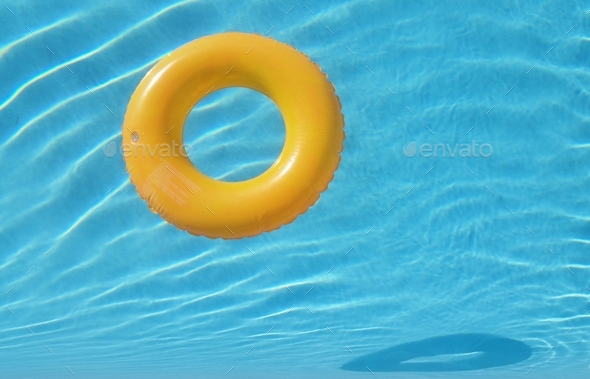 A yellow float for kids fun is floating in a swimming pool alone with ...