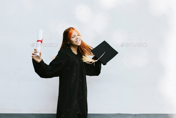 teenage girl in clothes of a graduate coat and cap celebrates high ...
