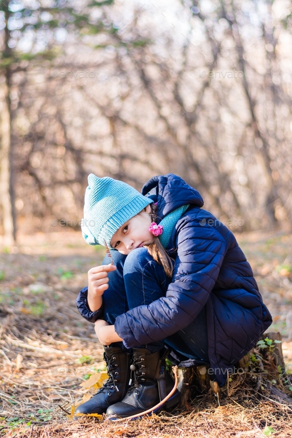 Sad girl sitting on a tree stump in a sunny forest in late autumn Stock ...