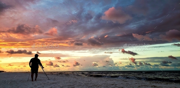 Silhouetted man with metal detector as hobby at sunset with beautiful ...