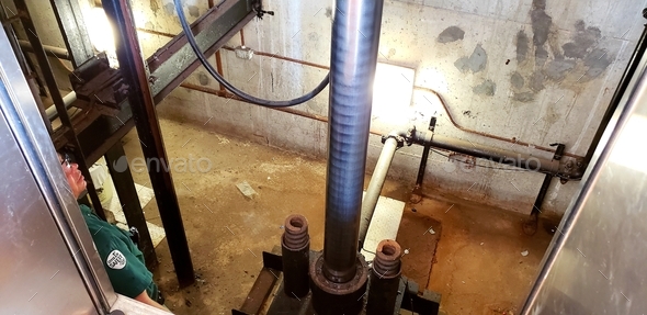 Elevator technician at bottom of elevator shaft hoping nobody going ...