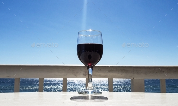 A glass of red wine goes with the beach in light and shadow overlooking ...