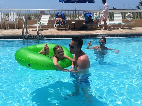 Dad pushing daughter in a float around the pool. Stock Photo by ...