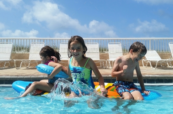 Happy people in swimming pool falling off float. Stock Photo by ...