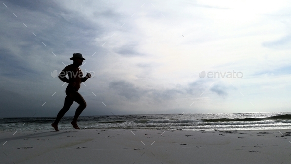 Men's health and fitness as an aging baby boomer running on the beach ...