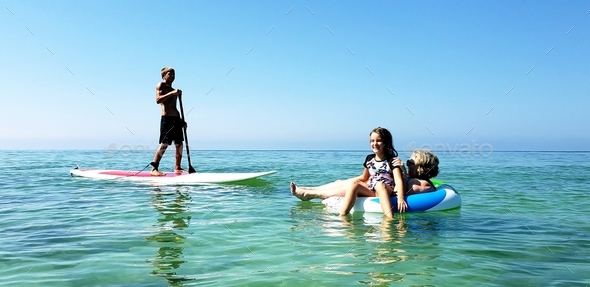 Happy kid with grandmother laying on a float on the water in the ocean ...