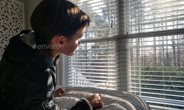 Hipster cool Gen z kid looking through blinds in a window to the ...