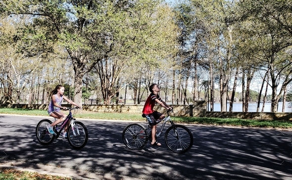 Kids fun as kids being kids ride bikes through park in spring. Stock ...