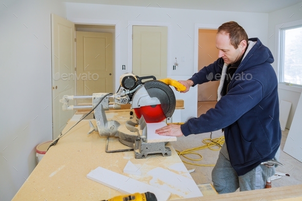 Builder uses circular saw tool to cut wood baseboard woodwork Stock ...