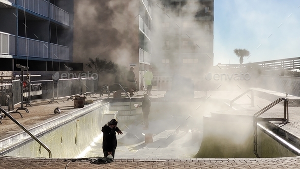 Workmen pouring acid on pool walls getting ready for new inside ...