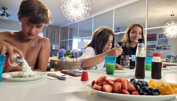 Generation z kids at kitchen countertop Eating healthy breakfast adding ...