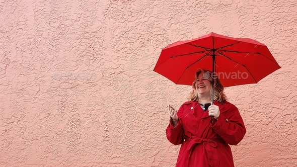 Active baby boomer in red raincoat and open umbrella as happy people ...