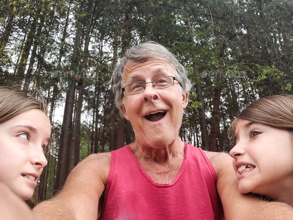 Active baby boomer grandparent taking a happy selfie with generation z ...