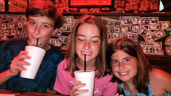 Generation z siblings sipping tea through a straw in restaurant booth ...