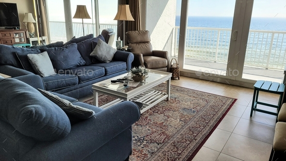Open concept family room in condo opens onto deck on beach with ocean ...