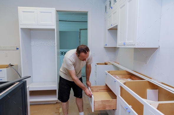 Installation of kitchen. Worker installs doors to kitchen cabinet ...