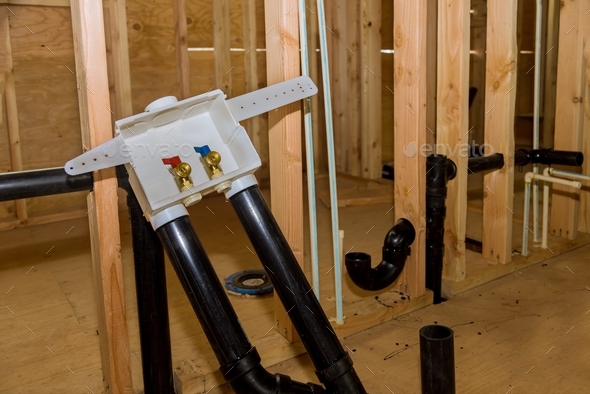 Plumber installing laundry outlet boxes with new home supplies washing ...