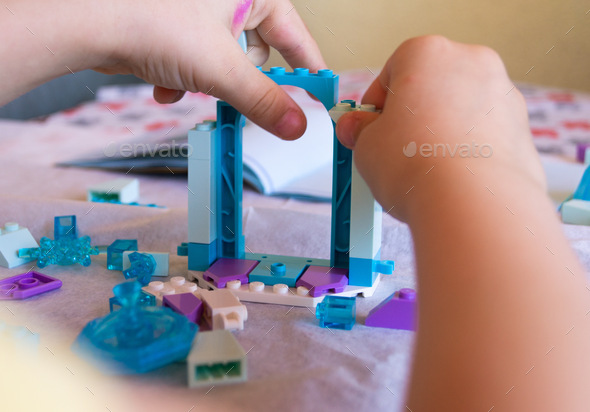 Kid playing Lego. Kids hand stacking up assembling Lego Frozen series ...