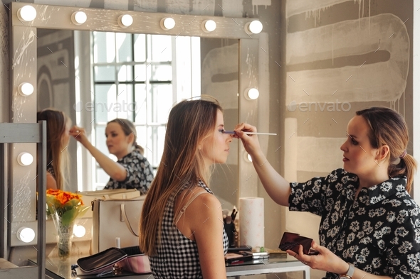 Make-up artist does makeup for a Caucasian woman with a beauty salon ...