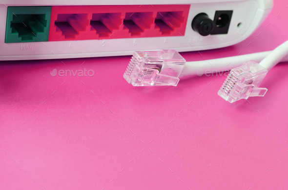 Internet router and Internet cable plugs lie on a bright pink ...